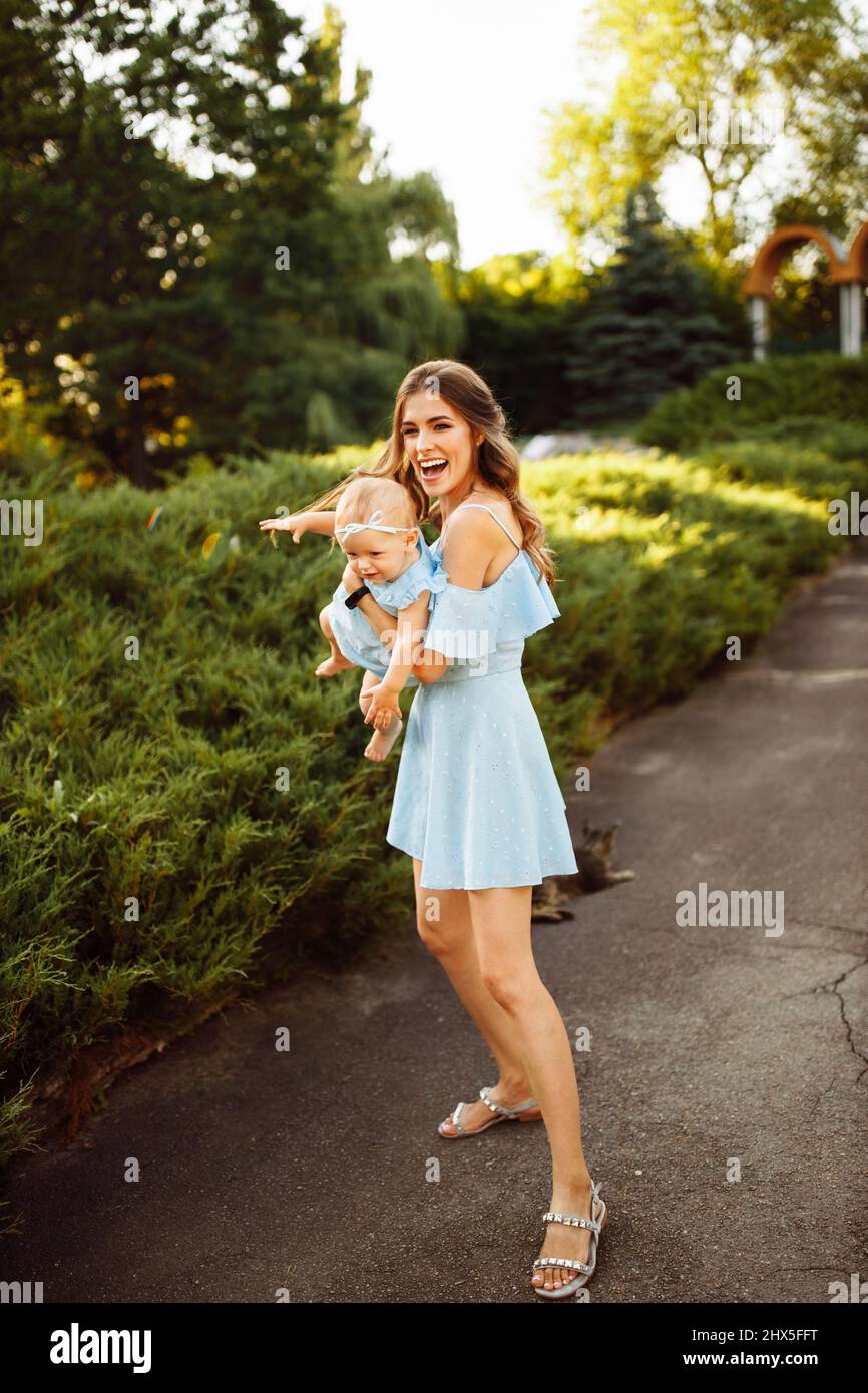 Overjoyed woman play with lovely baby girl at the park, adorable mother ...