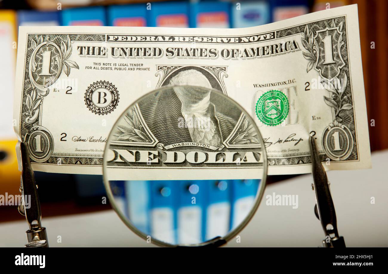 Inspecting every note. Shot of a one dollar bill under a magnifying ...