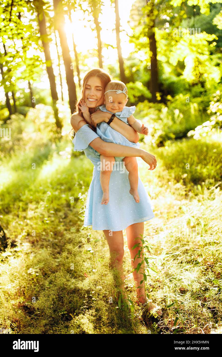 Overjoyed mother with adorable daughter at the park, smiling, hugging ...