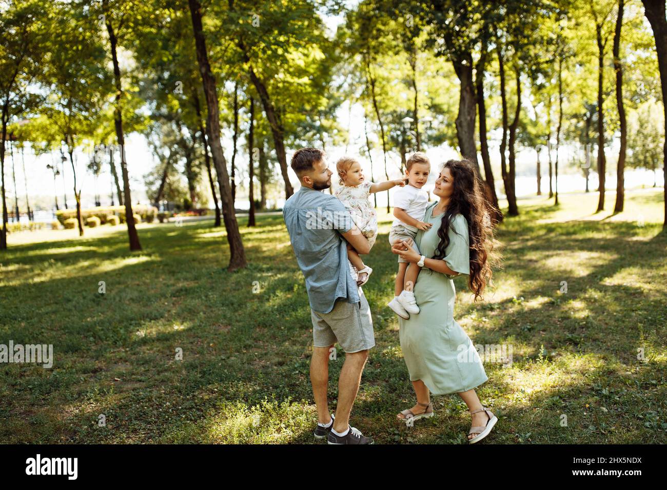Overjoyed parents with little children walking at the park, lovely mom ...