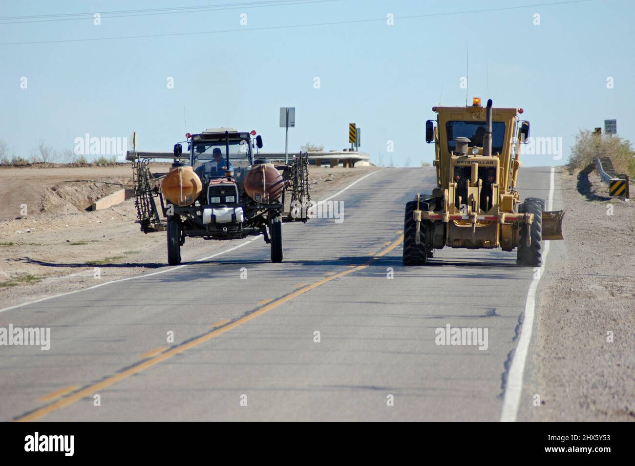 Farm tractors passing on farm road Stock Photo - Alamy