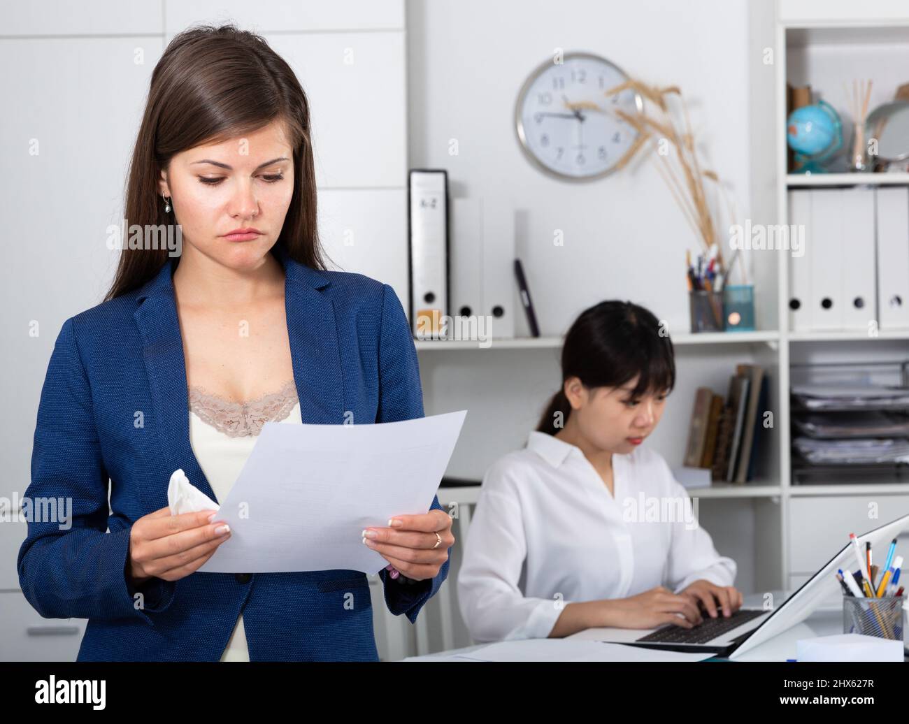 Business woman crying standing in office with working colleague behind ...