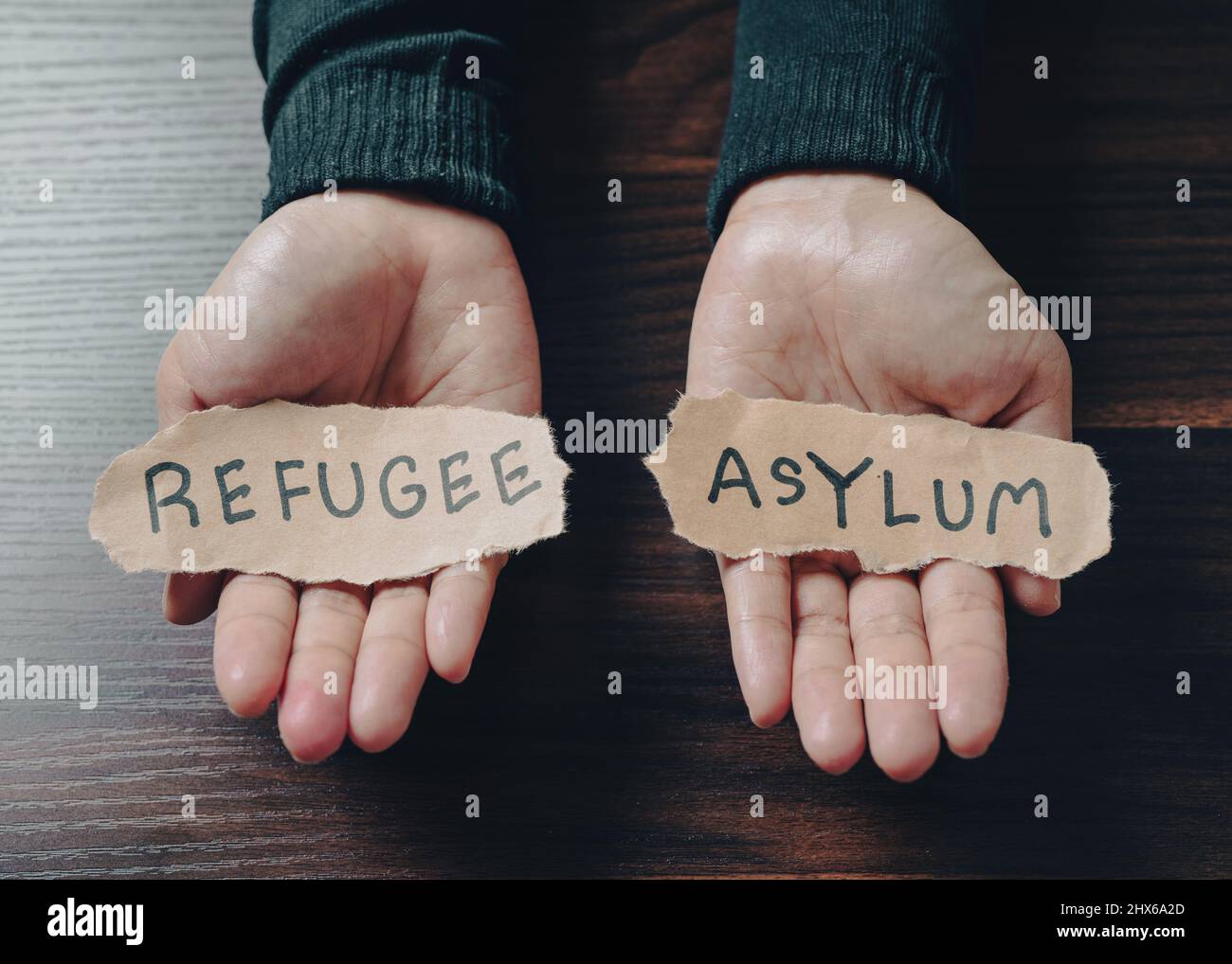 Hand with pieces of paper with words Refugee and Asylum message for ...