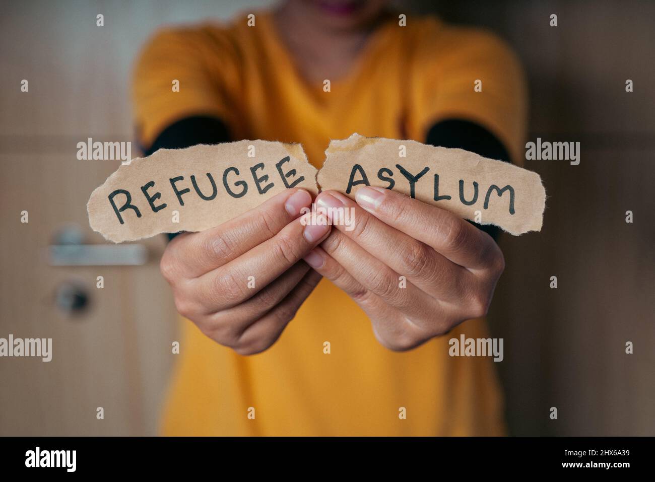 Hand with pieces of paper with words Refugee and Asylum message for ...