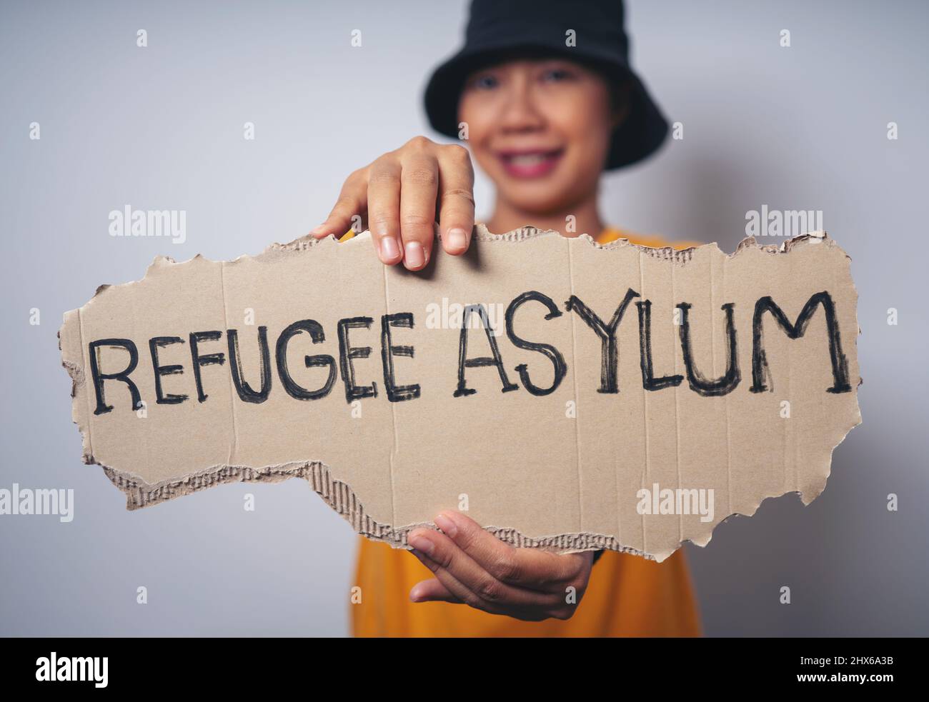 Hand with pieces of paper with words Refugee and Asylum message for ...