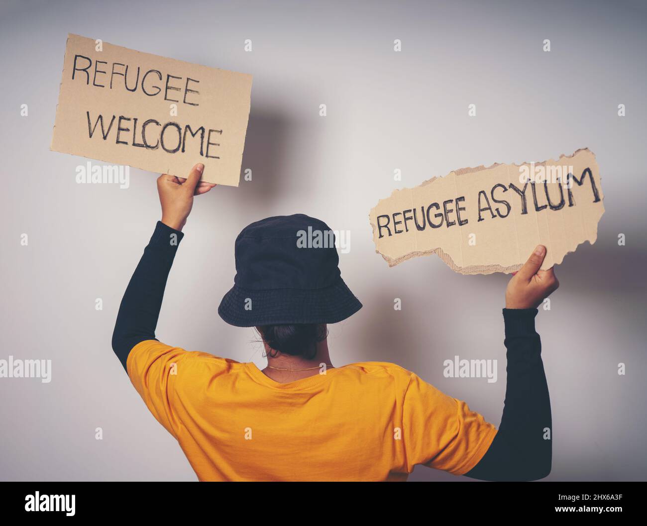 Woman holding pieces of paper with words Refugee Welcome and Refugee ...