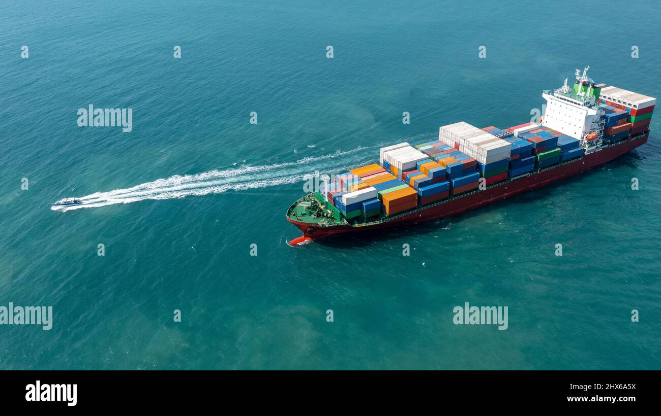 Aerial side view of cargo ship carrying container and running with ...