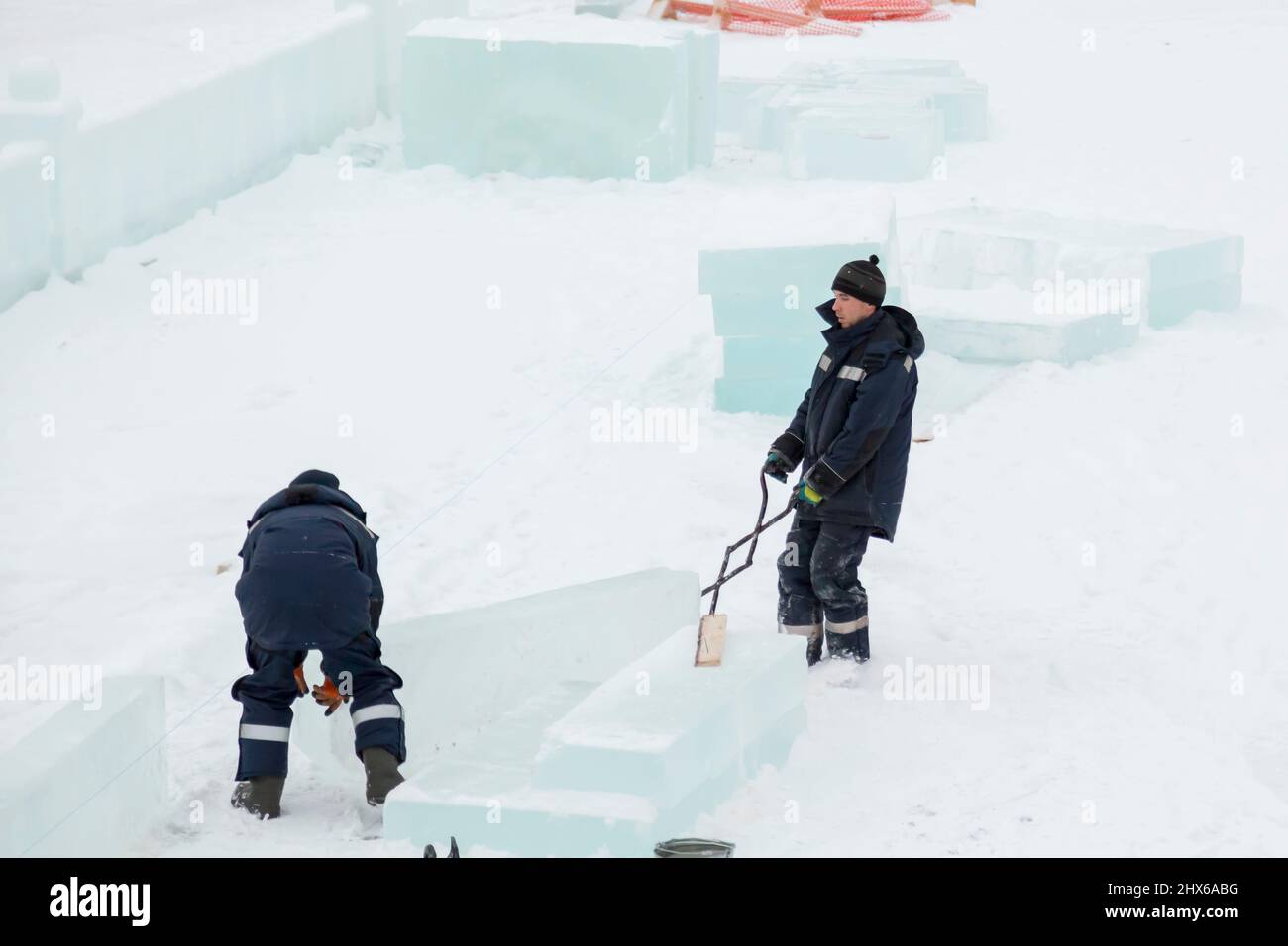 The worker pulls the ice block around the ice camp assembly site with ...