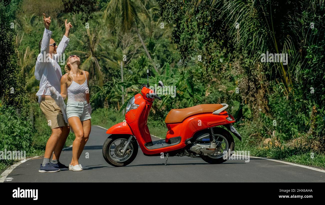 Two caucasian tourist woman man dance near scooter. Love couple on red ...