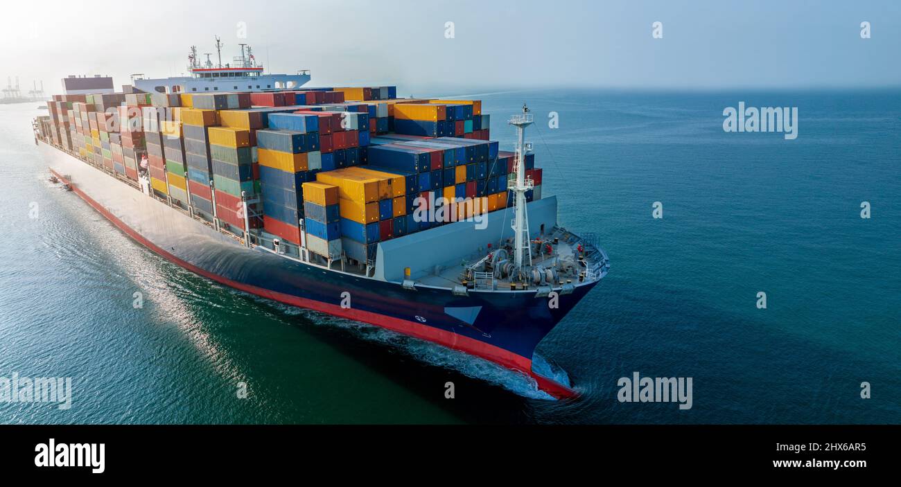 Aerial side view of cargo ship carrying container and running for ...