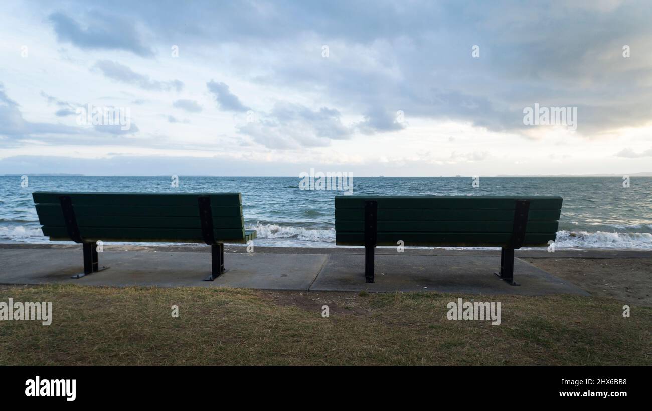 Empty bench facing the sea by the beach, Auckland Stock Photo - Alamy