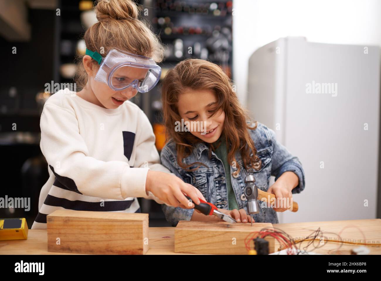 Playing with dads tools is the best. Shot of two little girls busy at ...