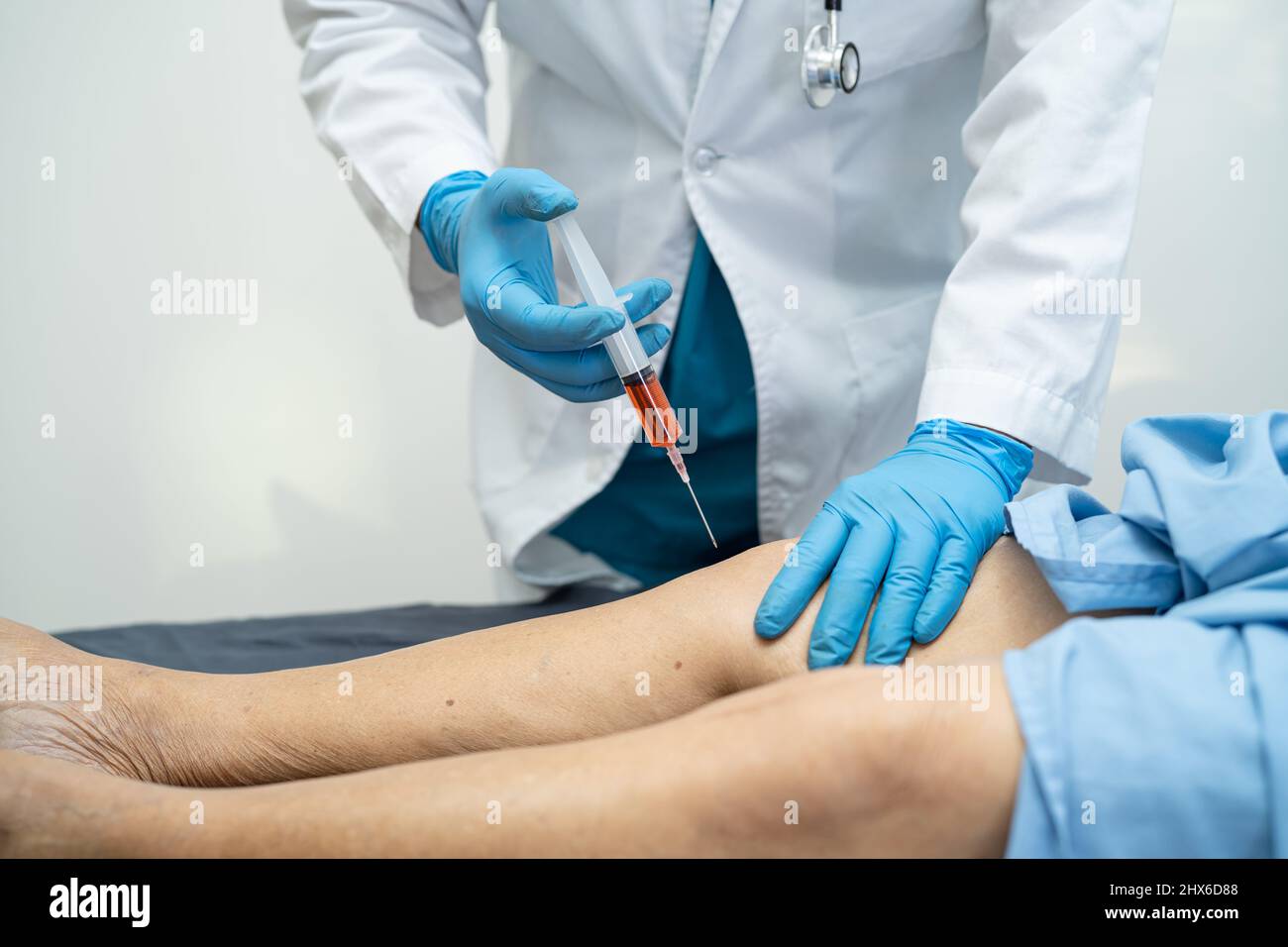 Asian doctor inject Hyaluronic acid platelet rich plasma into the knee of senior woman to walk ...