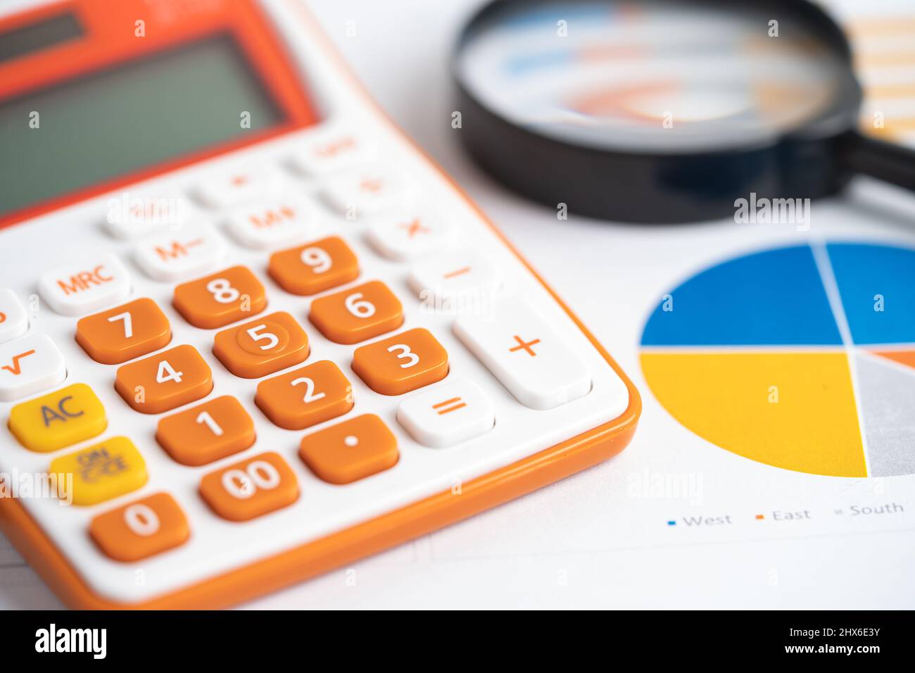 Magnifying glass and calculator on charts graphs paper. Financial ...