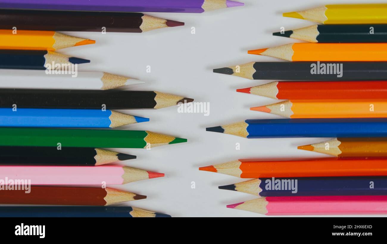 Many colored pencils are arranged around the edges of the image as a ...
