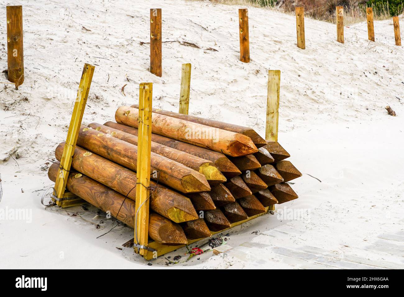 stack of thick round natural wooden fence posts with a sharpened end to ...