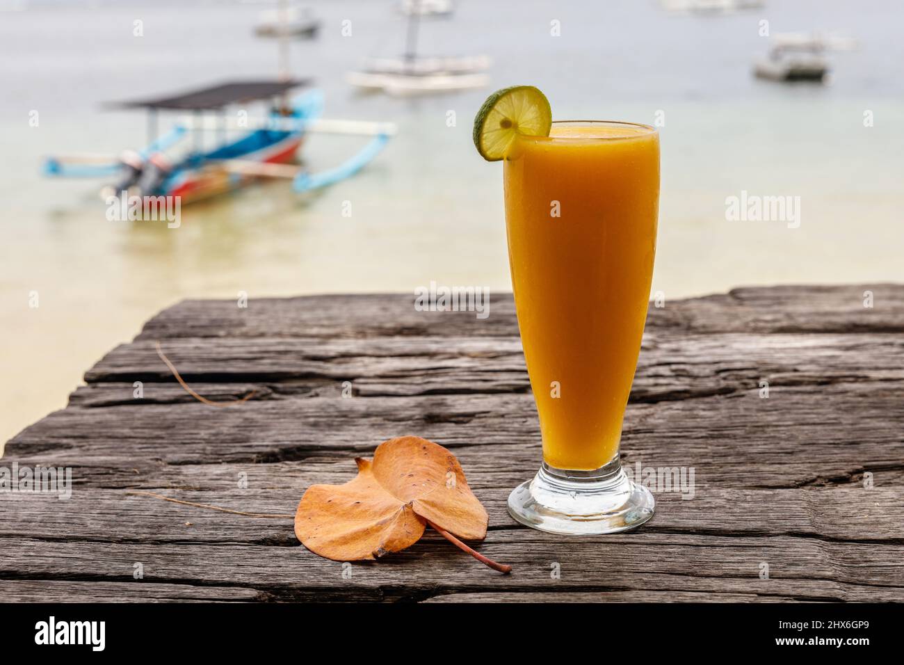 Mango juice on the beach with the sea and a boat on the background ...