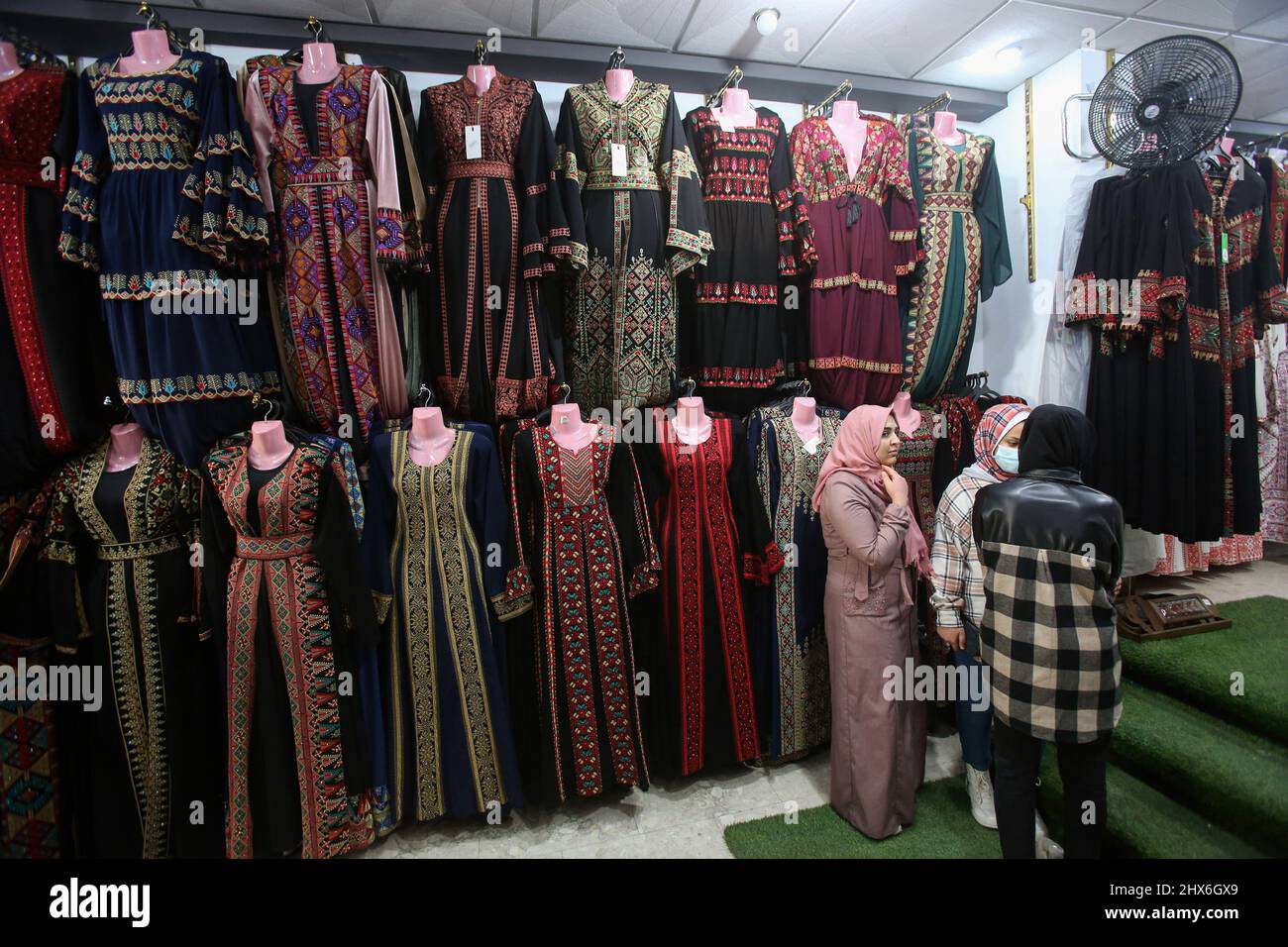 Palestinian adults take a look at Palestinian traditional dresses in a ...