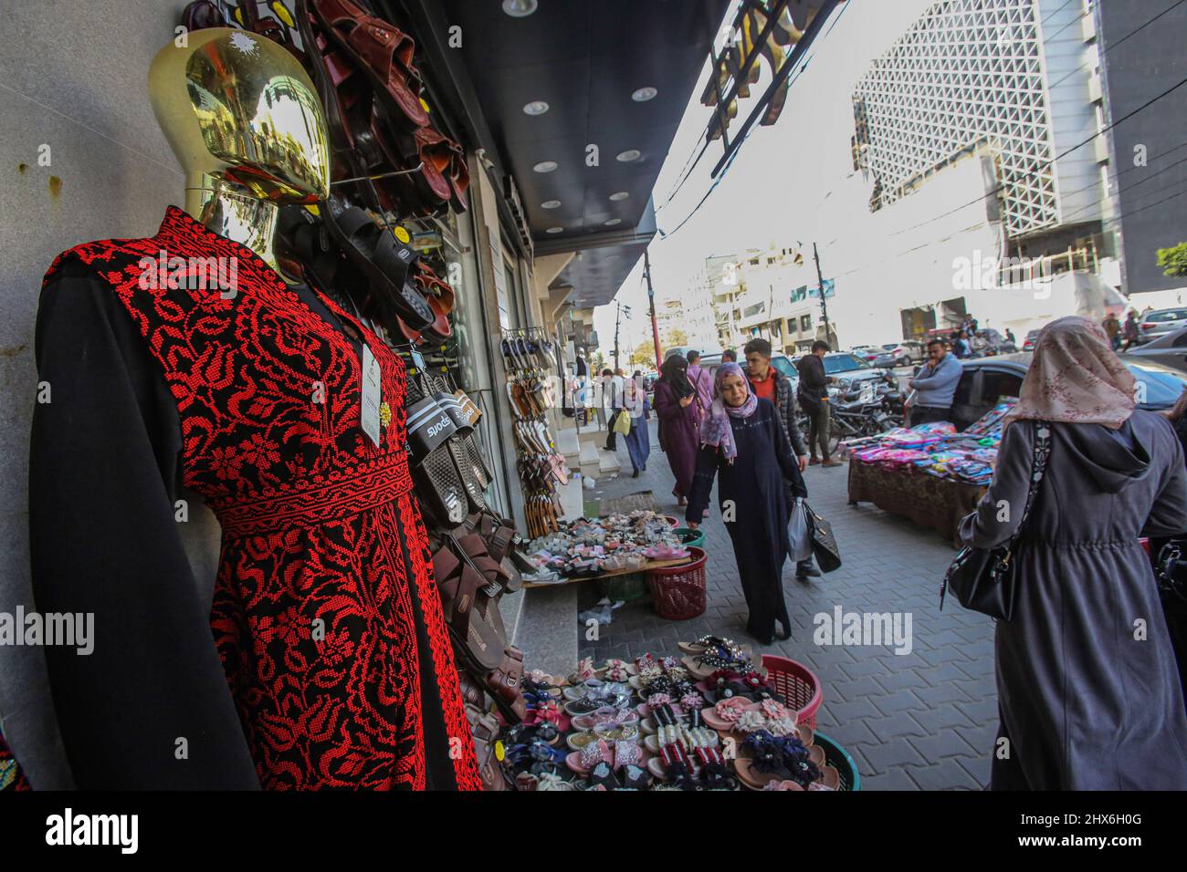 Palestinians walk past a Palestinian traditional dress at a Shop in ...