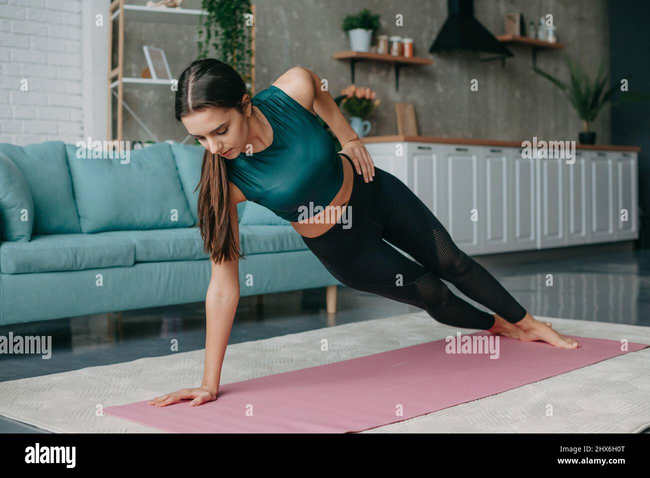 Caucasian standing in side plank on one hand at home, training body ...