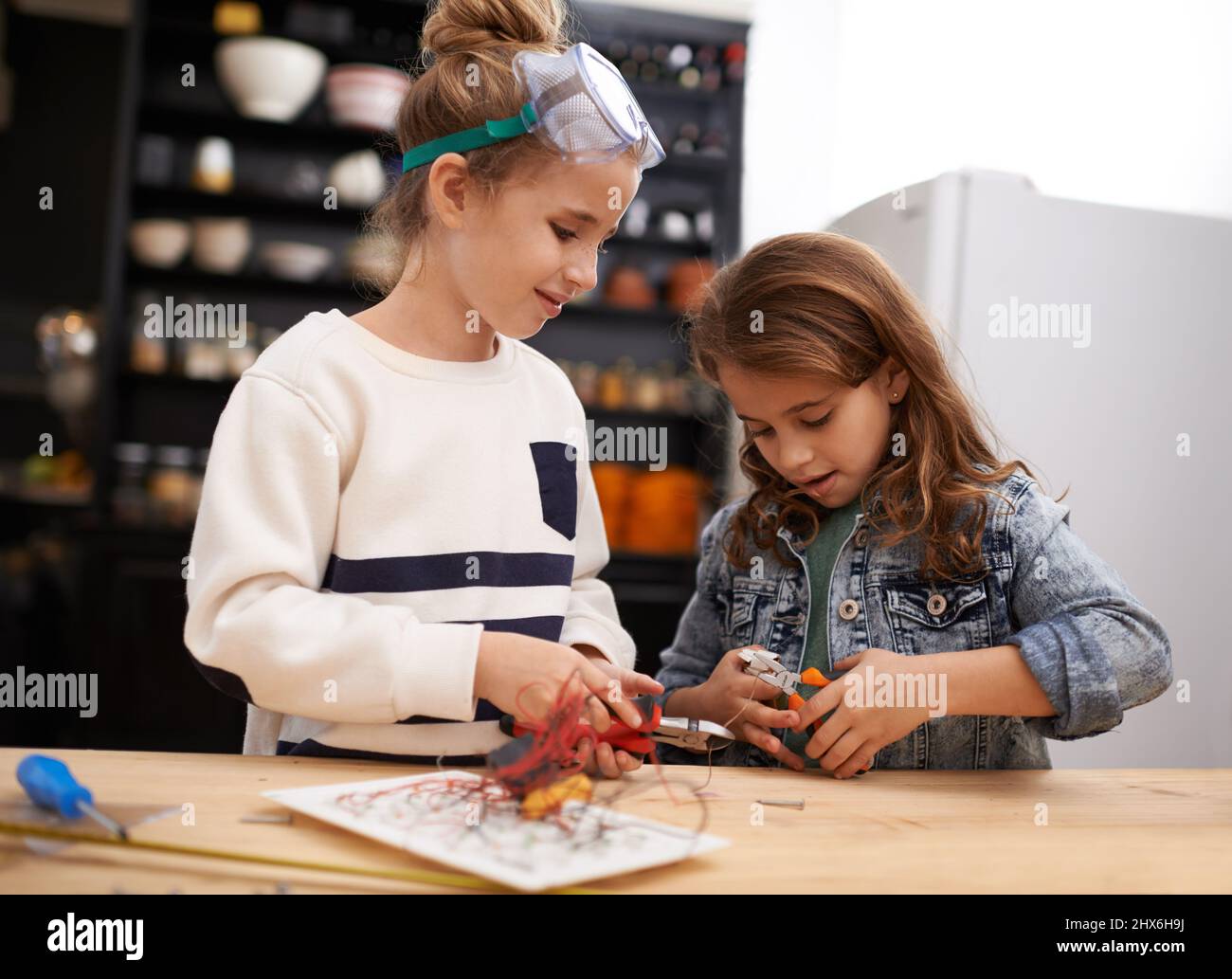 Fixing things together. Shot of a two little girls helping each other ...