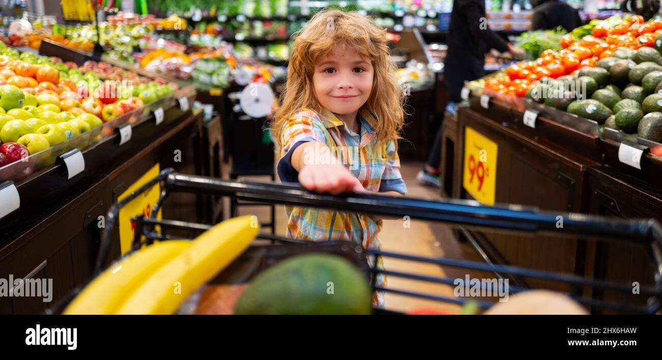 Child shopping in supermarket. Little child choosing fresh vegetables ...