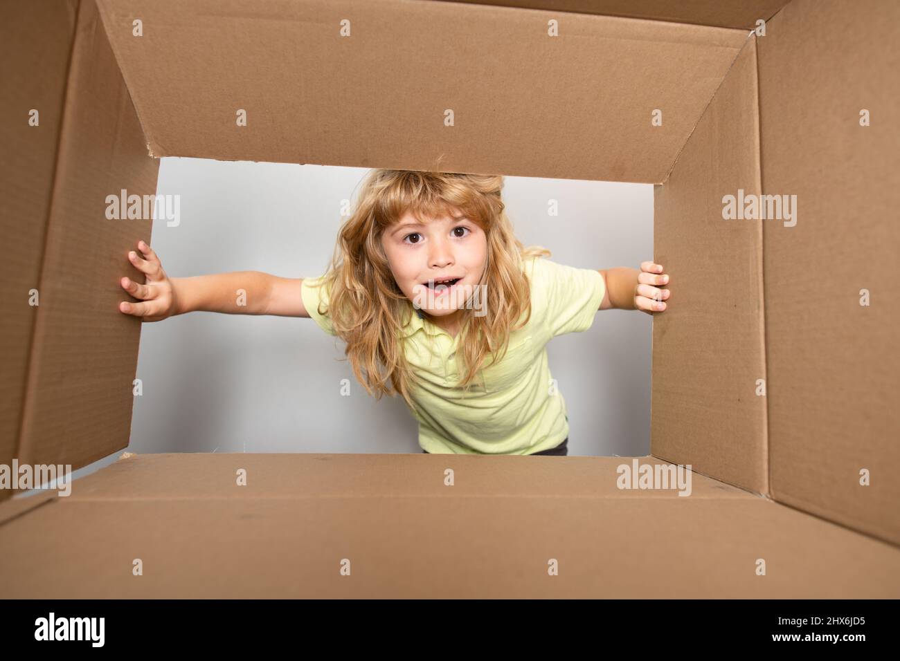 Cheerful cute child opening a present. Cardboard boxes, parcels ...