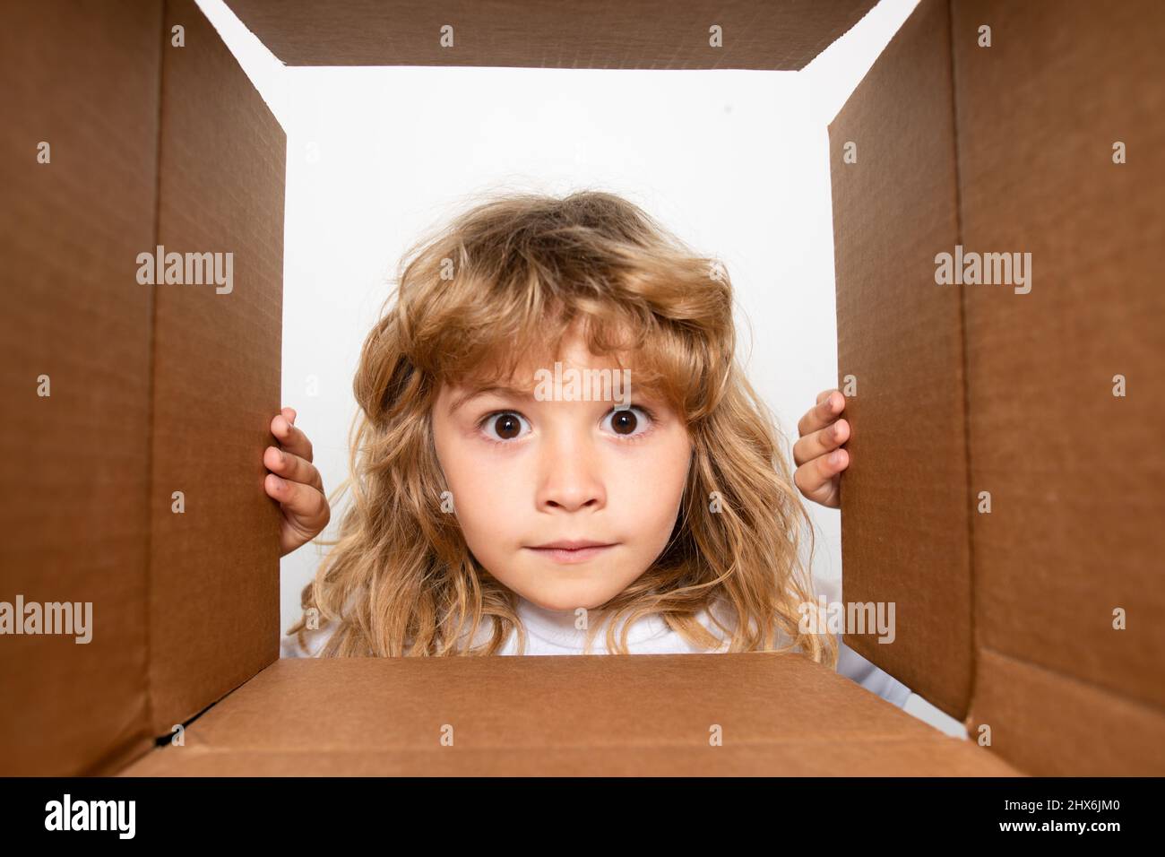 Surprised kid unpacking and opening carton box, and looking inside with ...
