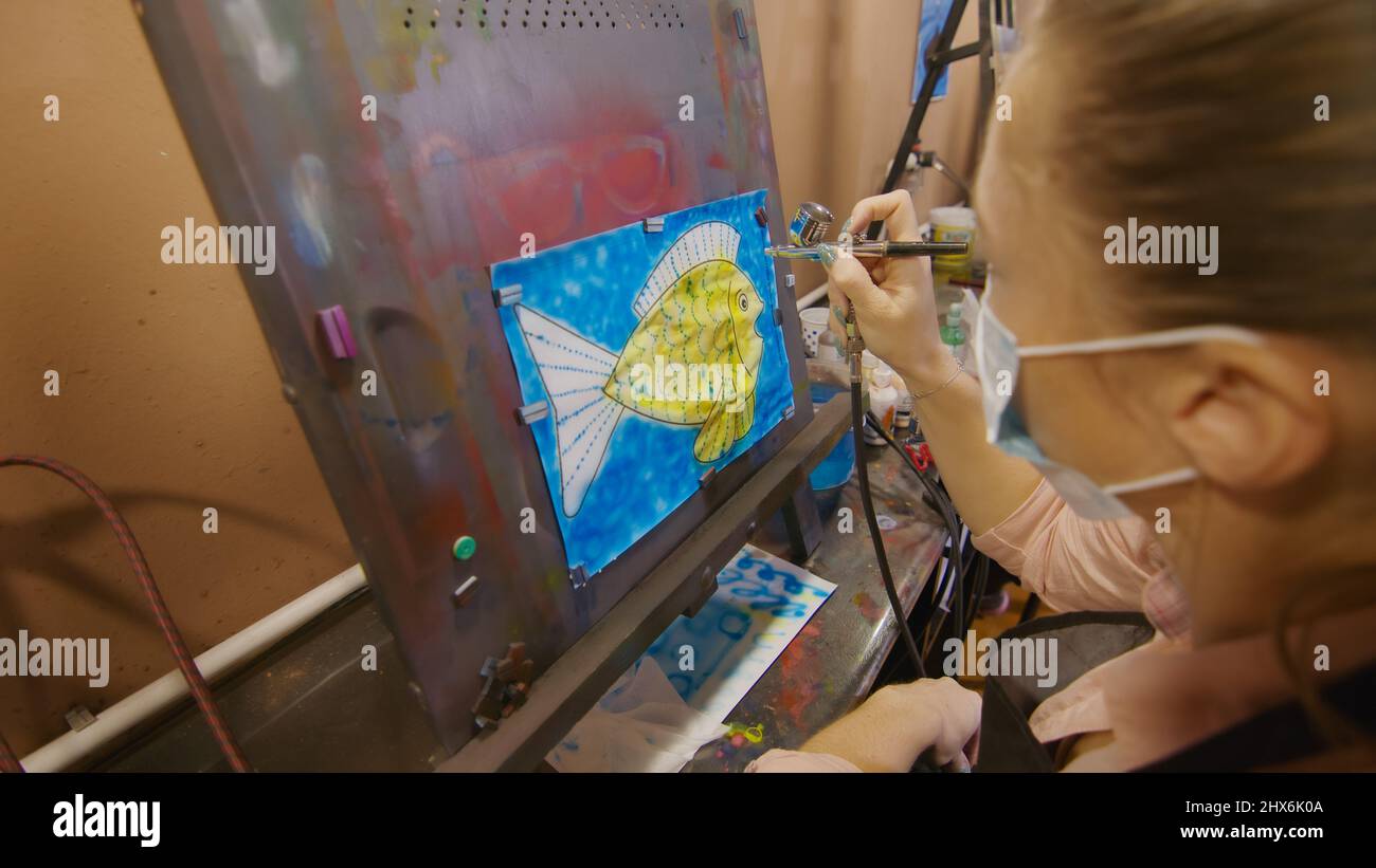 Woman artist learns to paint with airbrush with acrylic dye, paper and ...