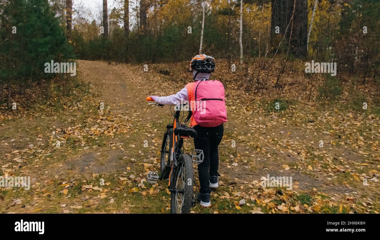 One caucasian children walk with bike in autumn park. Little girl ...