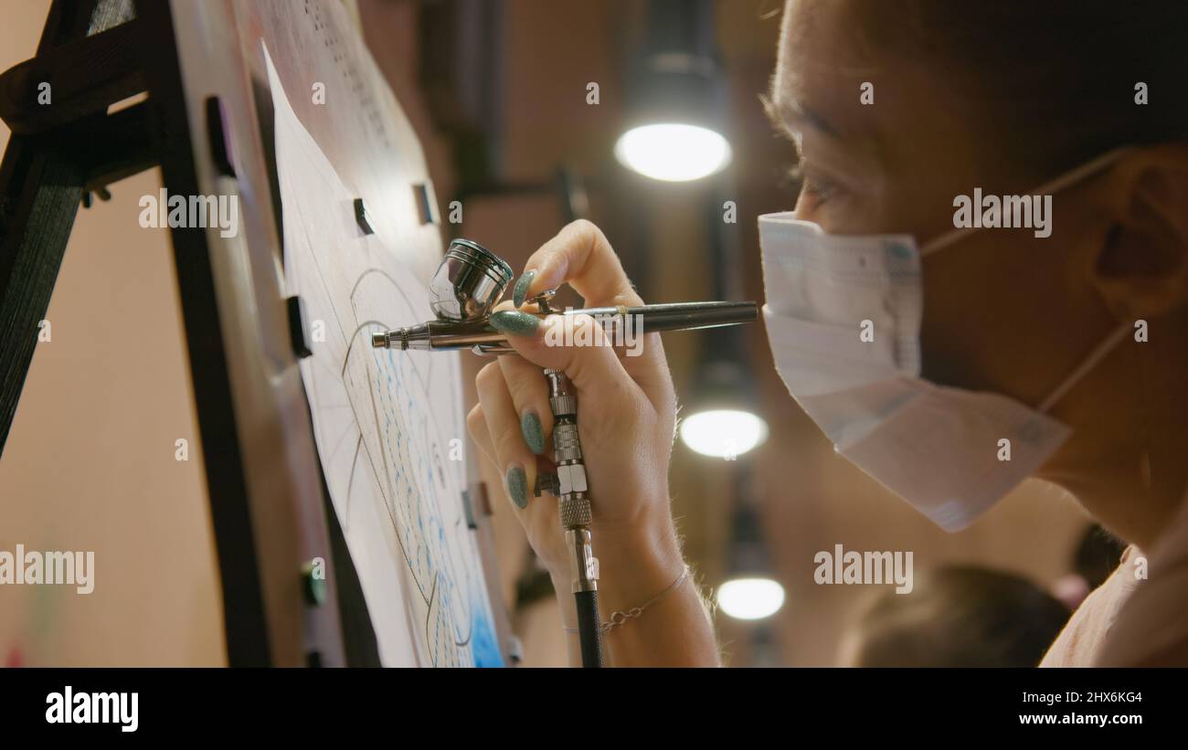 Woman artist learns to paint with airbrush with acrylic dye, paper and ...