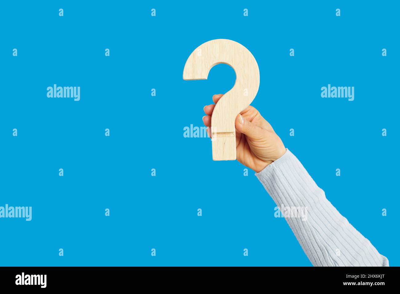 Human hand holding question mark against blank blue background for FAQ ...
