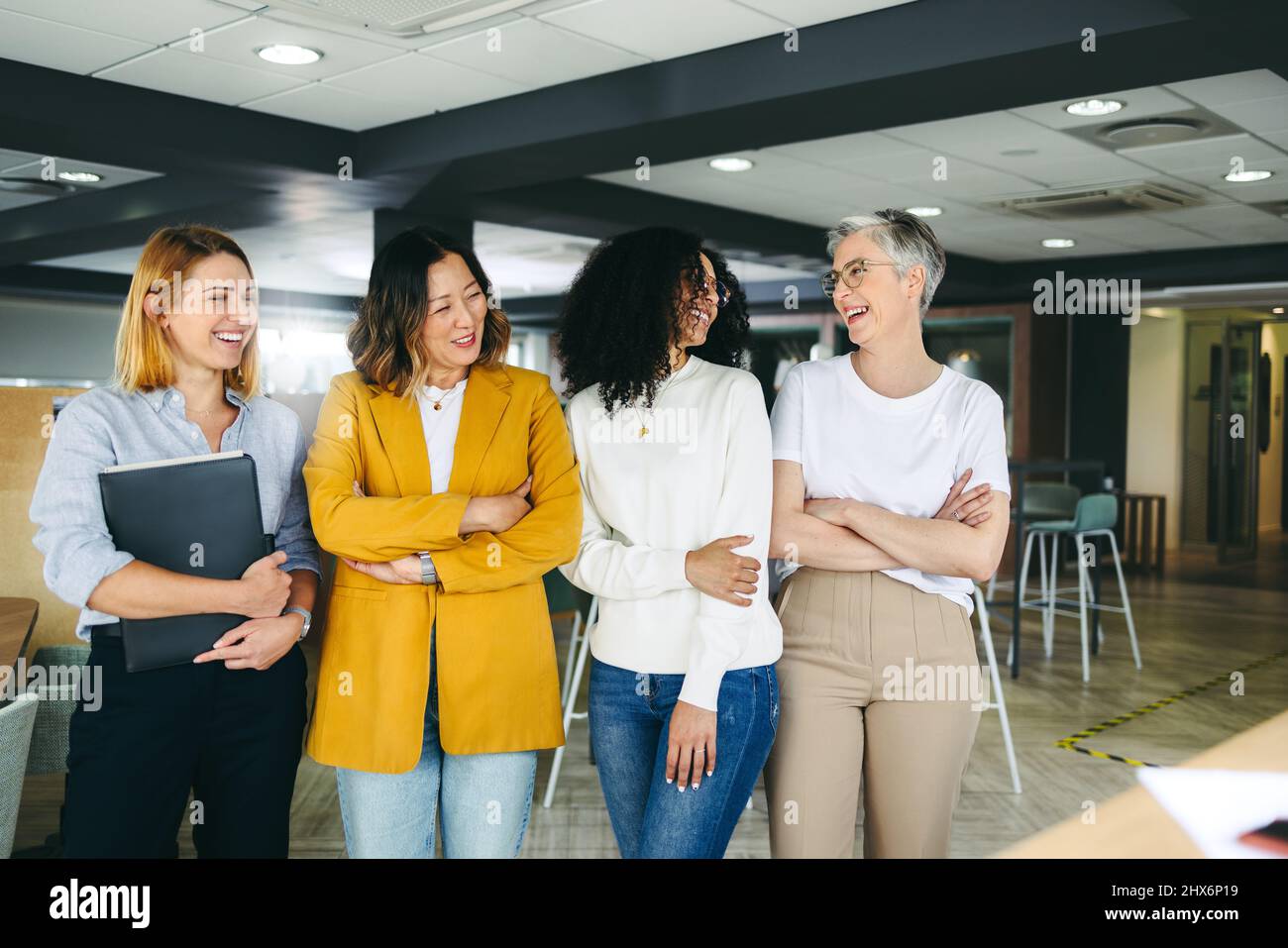 Multicultural businesswomen laughing happily while standing in a co ...