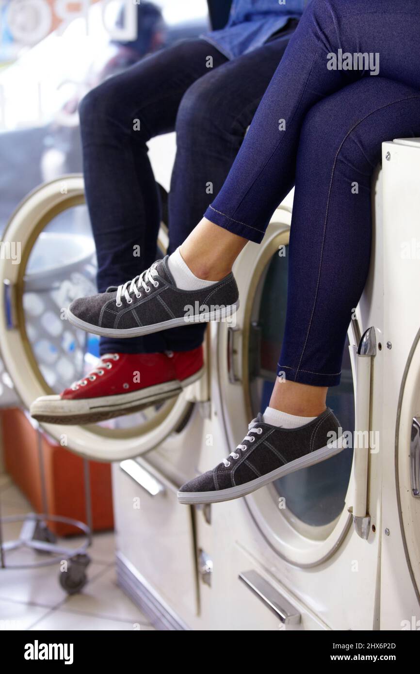 Waiting for their washing. Cropped image of a couples legs and feet as ...