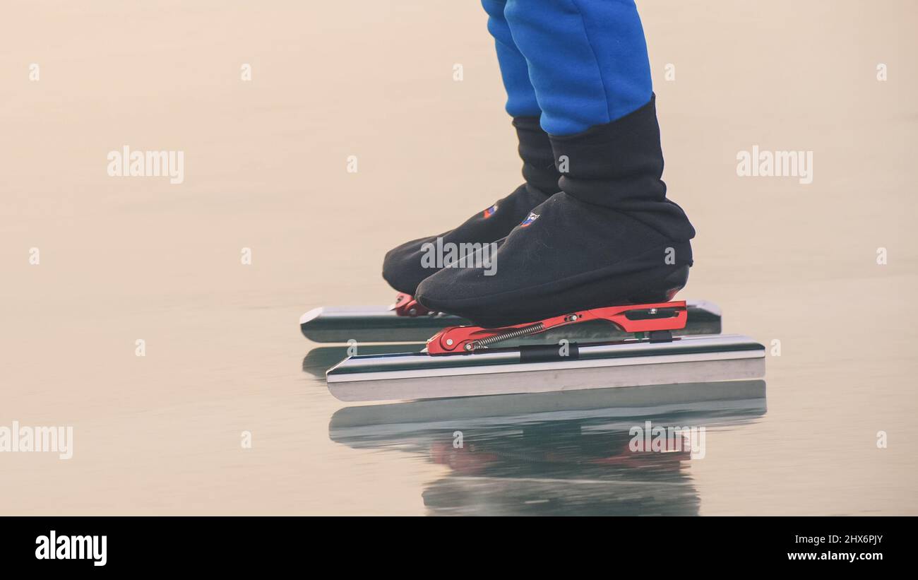 The child train on ice speed skating. The legs in skates close up. The ...