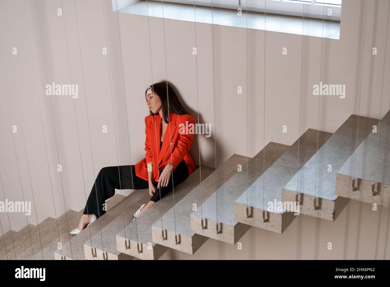 Beautiful business woman on stairs in red jacket is experiencing ...
