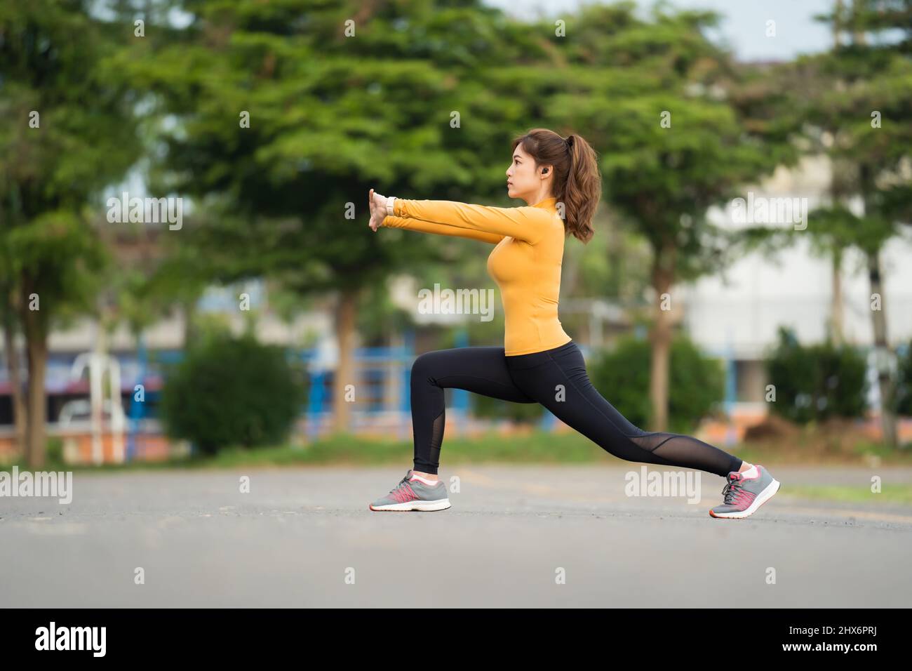 young woman runner stretching legs before run in the park Stock Photo - Alamy