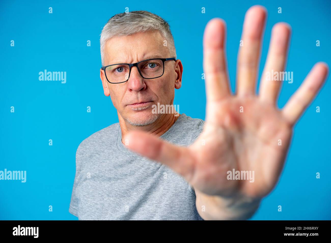 Middle age senior man over blue background doing stop sign with palm of ...
