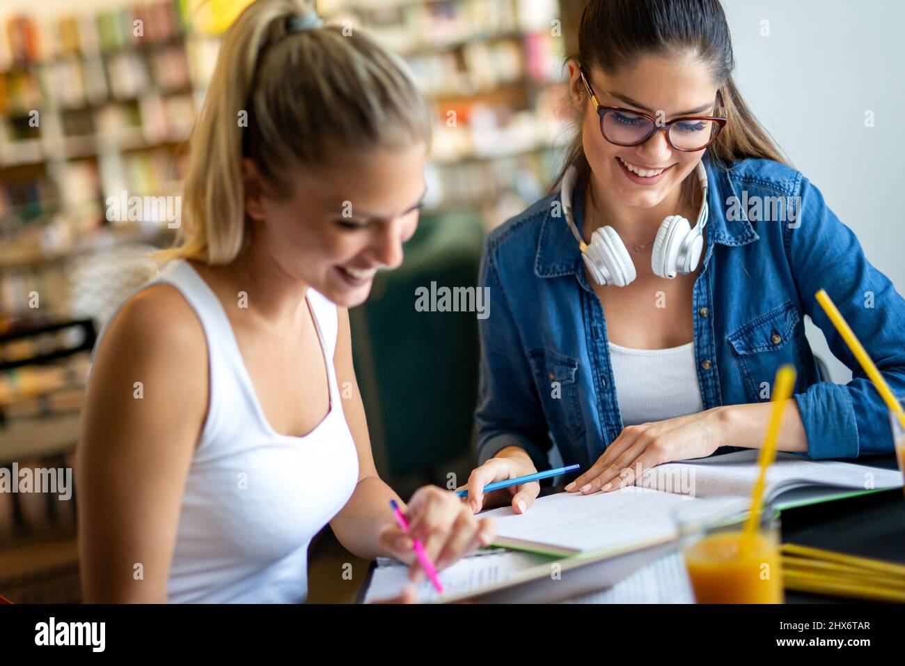 Happy young university students studying with books in library Stock ...