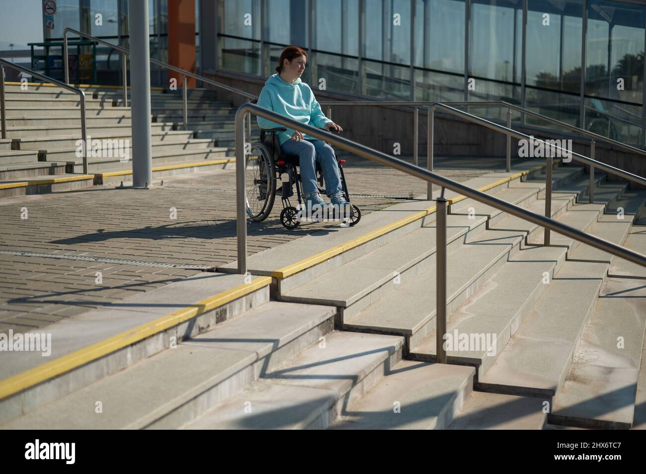 A caucasian woman in a wheelchair cannot go down stairs without a ramp ...