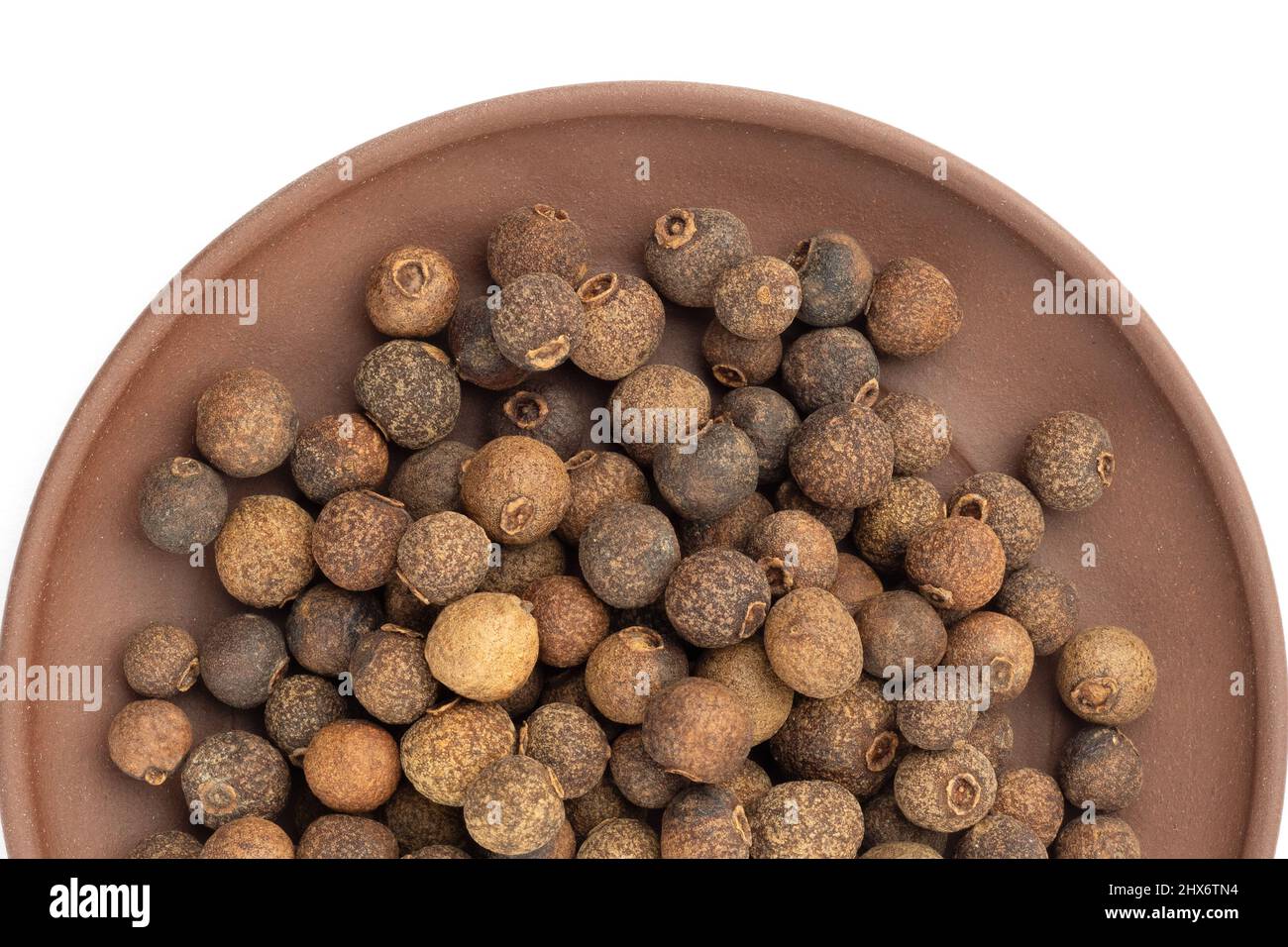 Spice Allspice in clay plate on white background. Flat lay. Close up ...