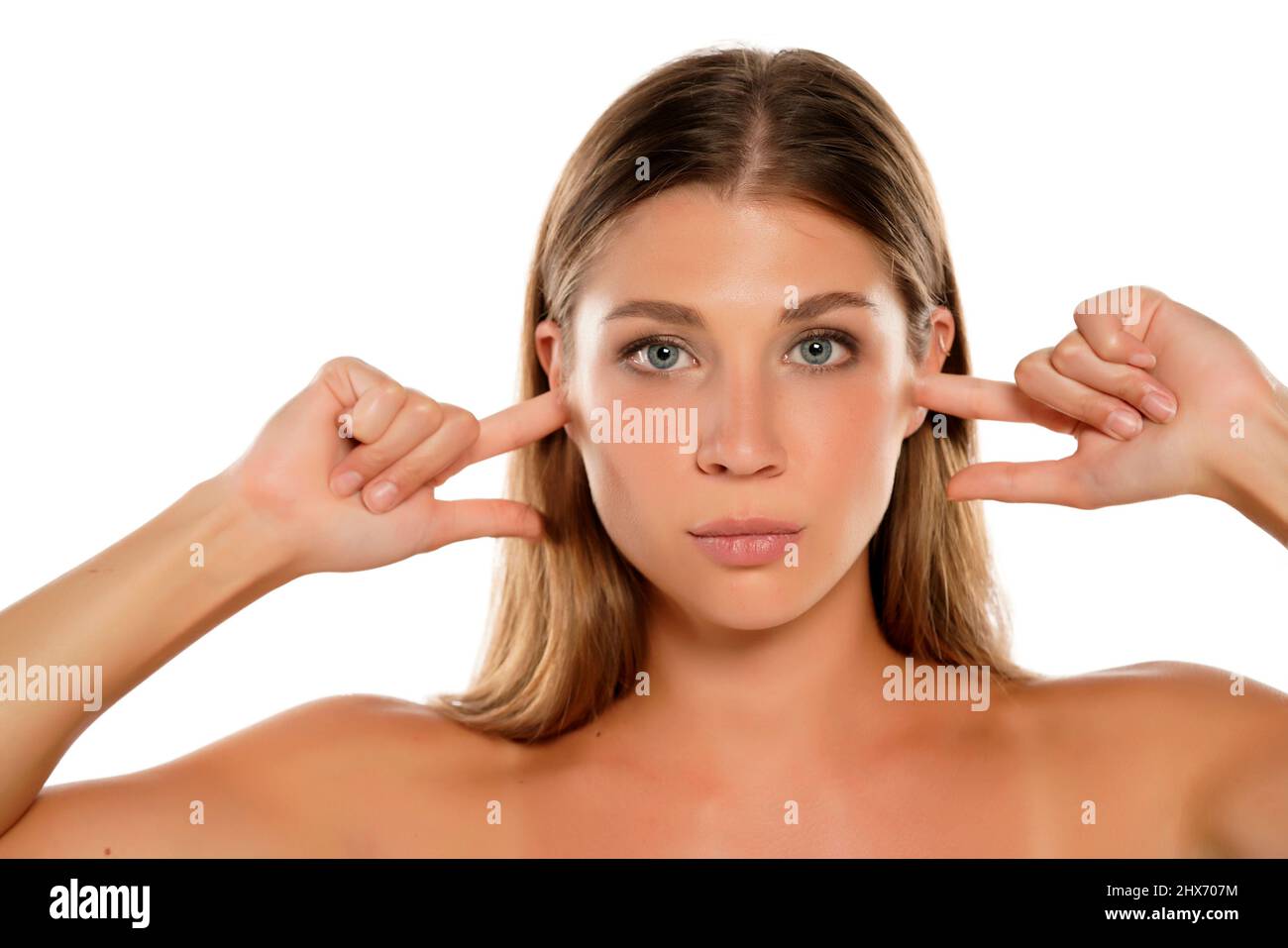 a young beautiful woman with blue eyes closes her ears with her fingers ...