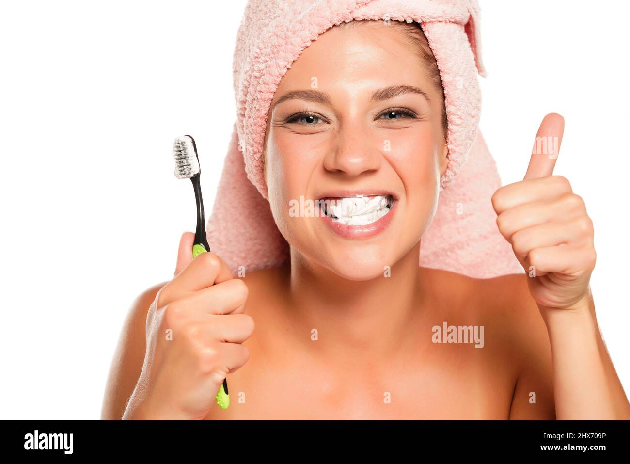 young woman posing with tootbrush and showing thumbs up white ...