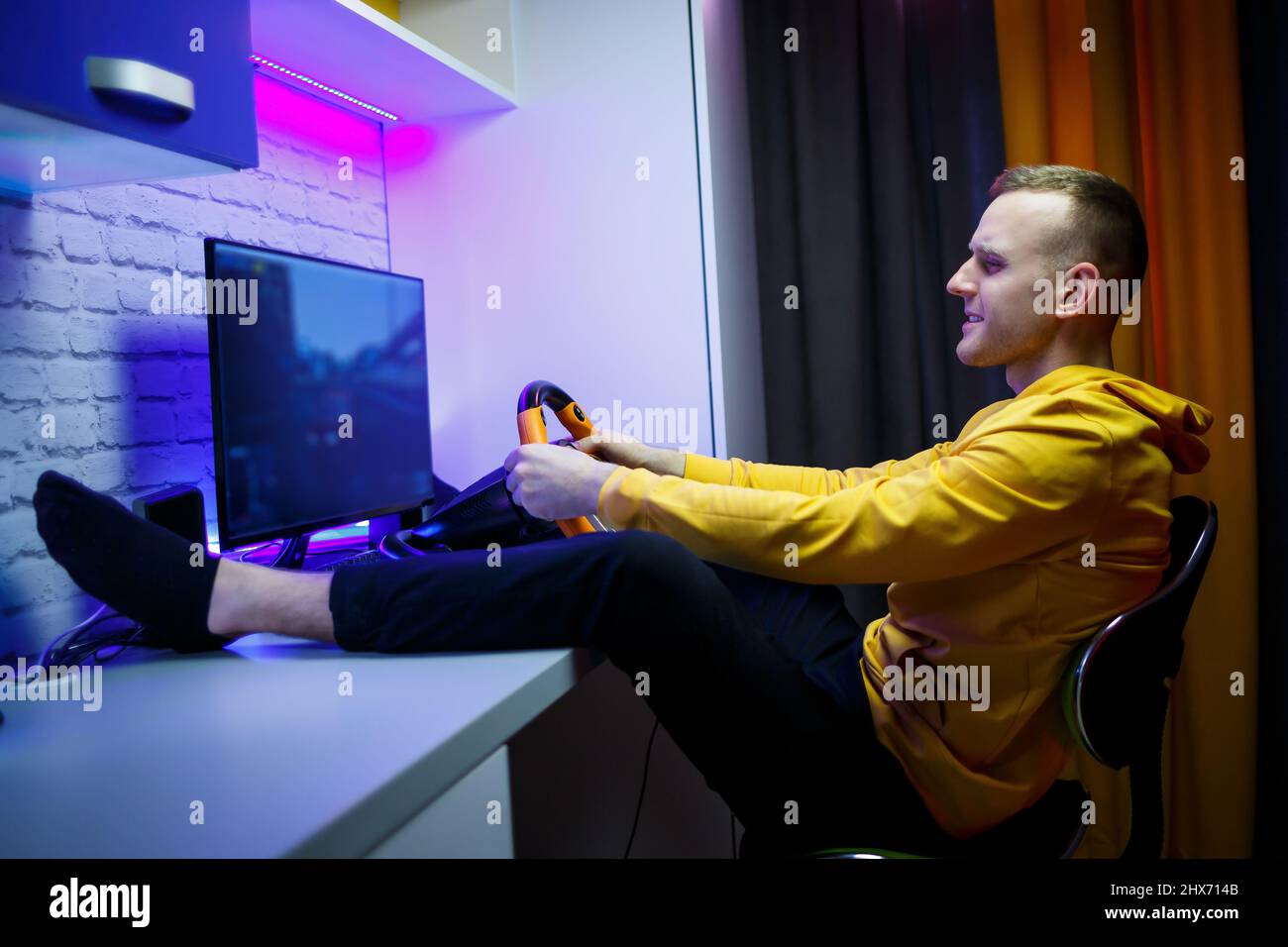 Male gamer playing racing games on the computer. He uses the steering ...