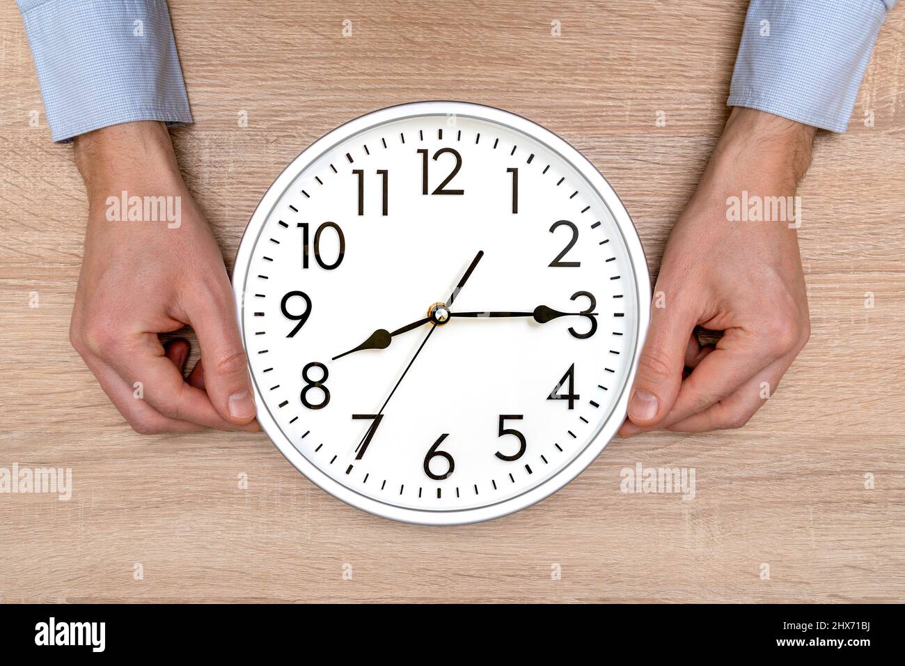 Male hands holding wall clock. Time management concept Stock Photo - Alamy