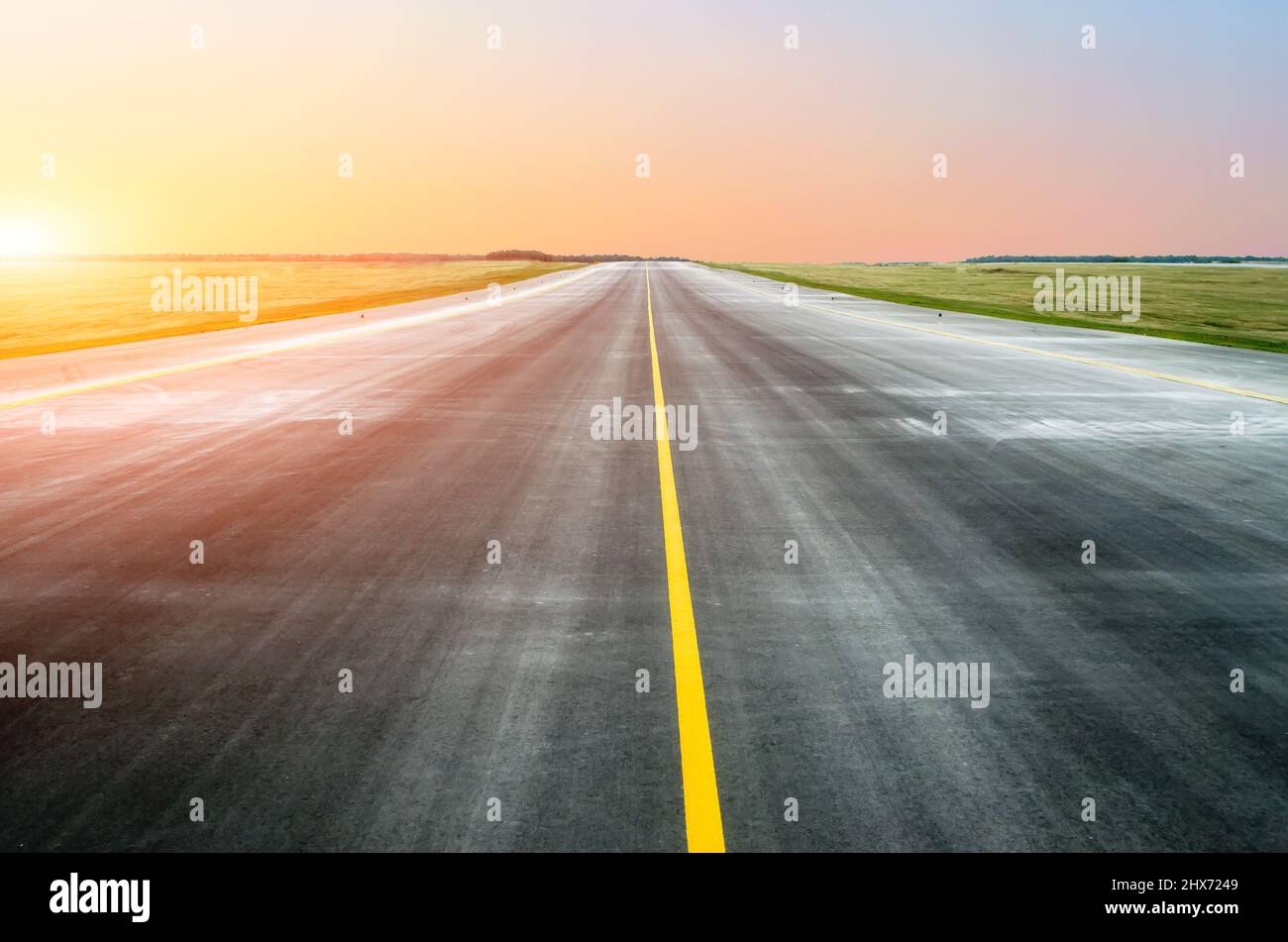 Asphalt road with a dividing strip in the horizon at sunset Stock Photo ...