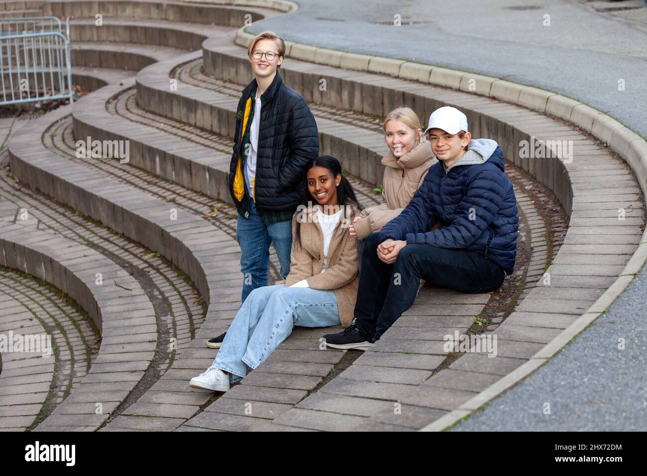 Portrait of smiling teenage friends sitting on steps Stock Photo - Alamy