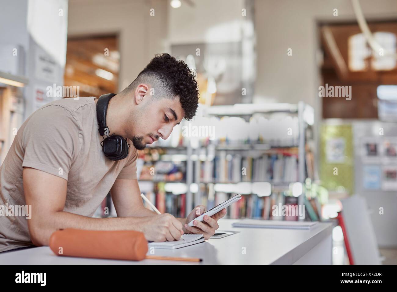 Male student taking notes in library Stock Photo - Alamy