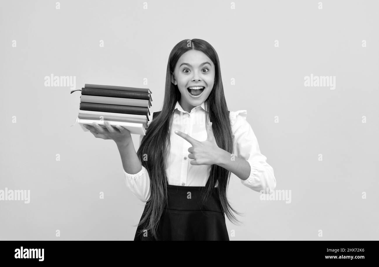 surprised teen girl in school uniform pointing finger on book stack ...
