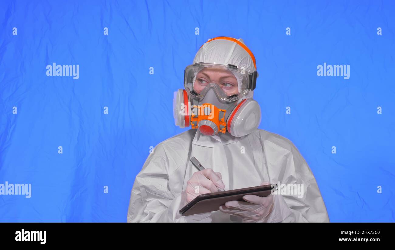 Scientist virologist in respirator makes write in an tablet computer ...